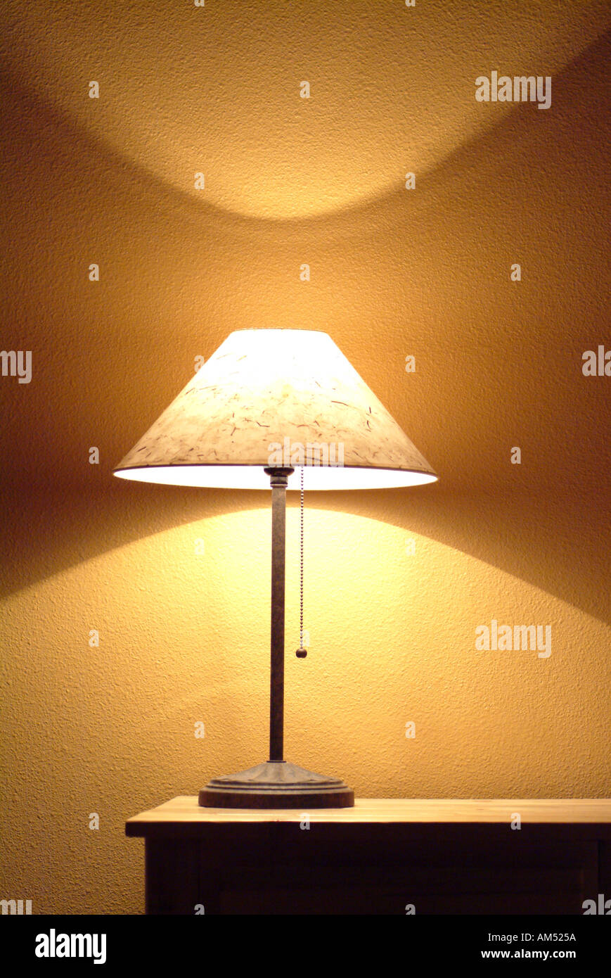 end table with a lamp throwing a glow on the wall Stock Photo - Alamy