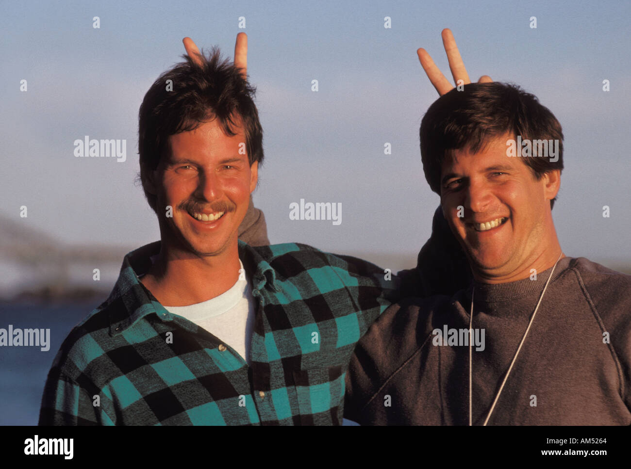 Two brothers pose for a photo and they both put fingers in a V shape up ...