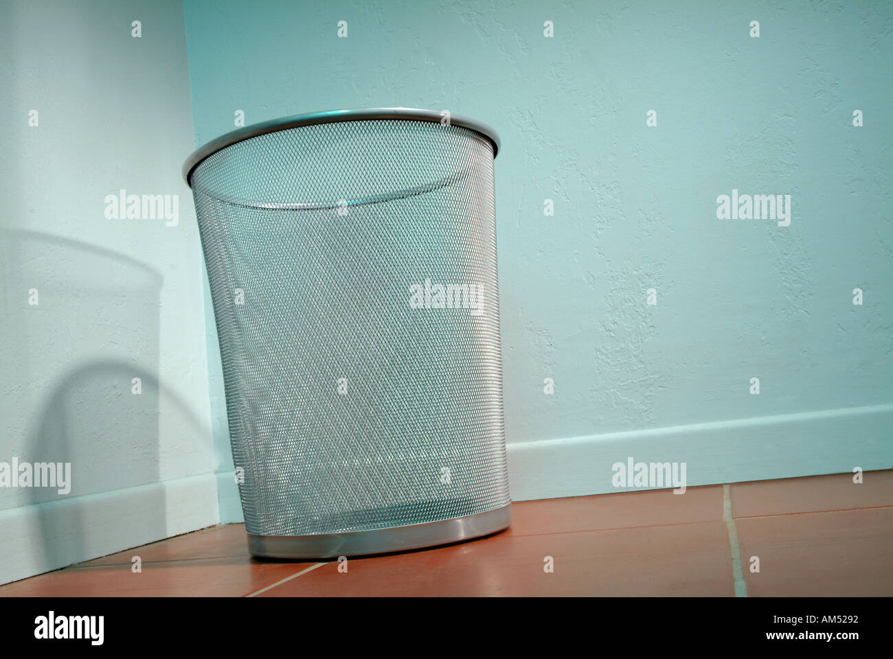 An empty wire mesh trash can in the corner of a room Stock Photo - Alamy