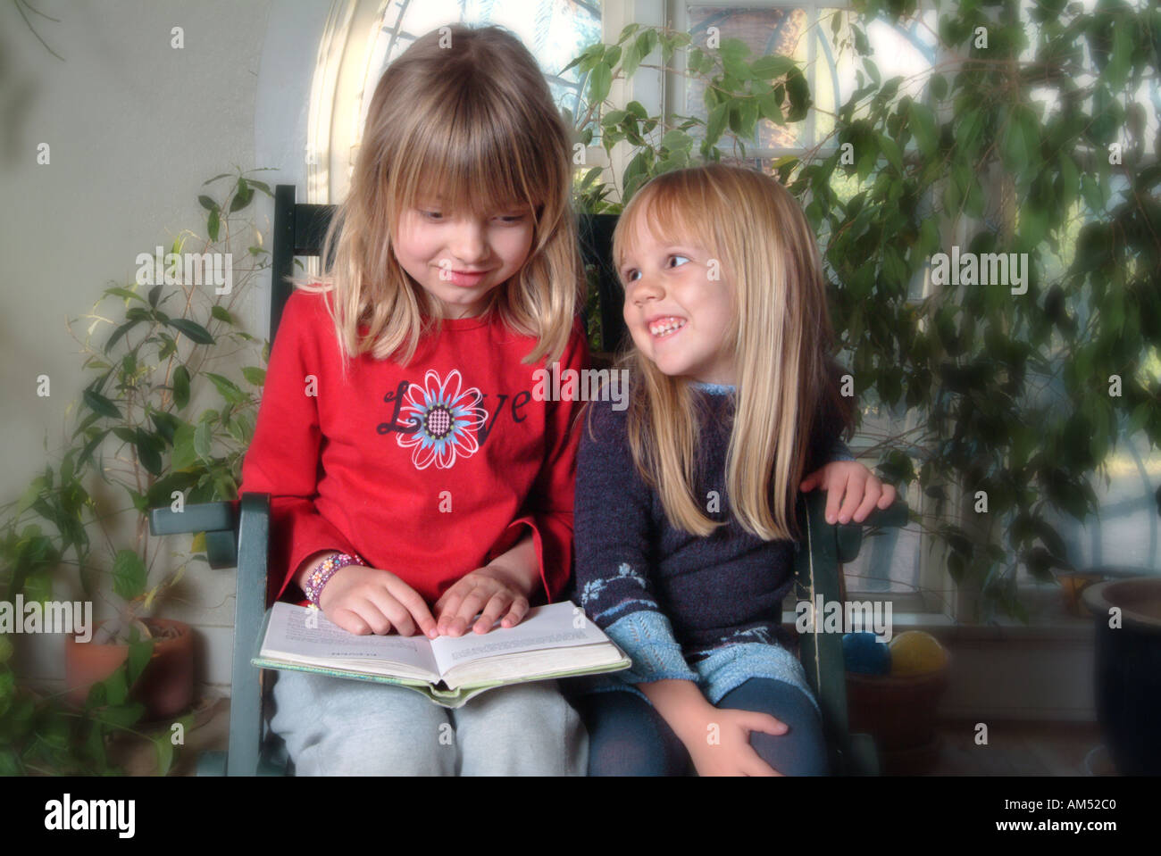 two girls who are best friends reading a book Stock Photo - Alamy