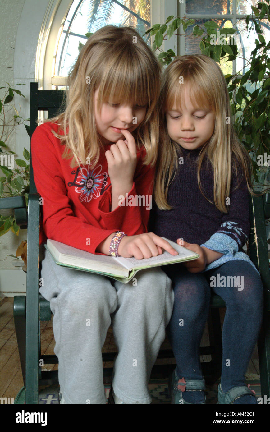 two girls who are best friends reading a book together Stock Photo - Alamy