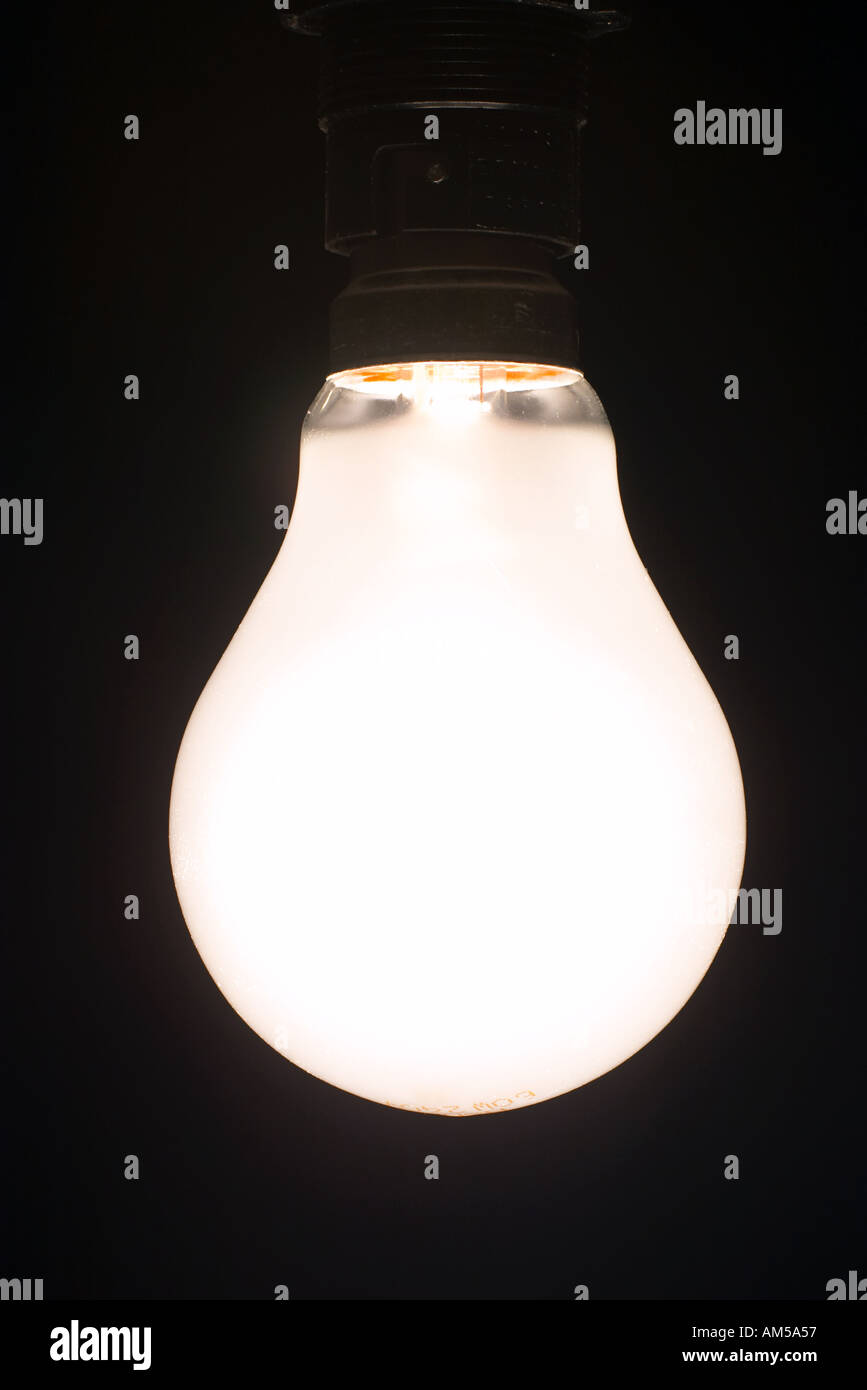 Shining lightbulb against black background Stock Photo - Alamy