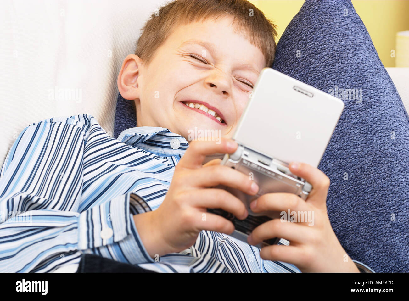 Boy on sofa playing with Gameboy Stock Photo - Alamy
