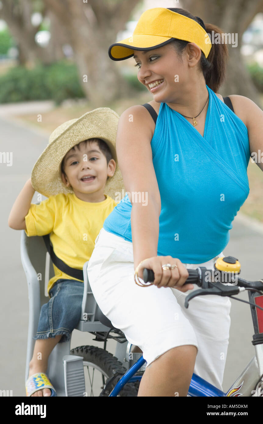 Mid adult woman riding a bicycle with her son sitting behind her Stock ...