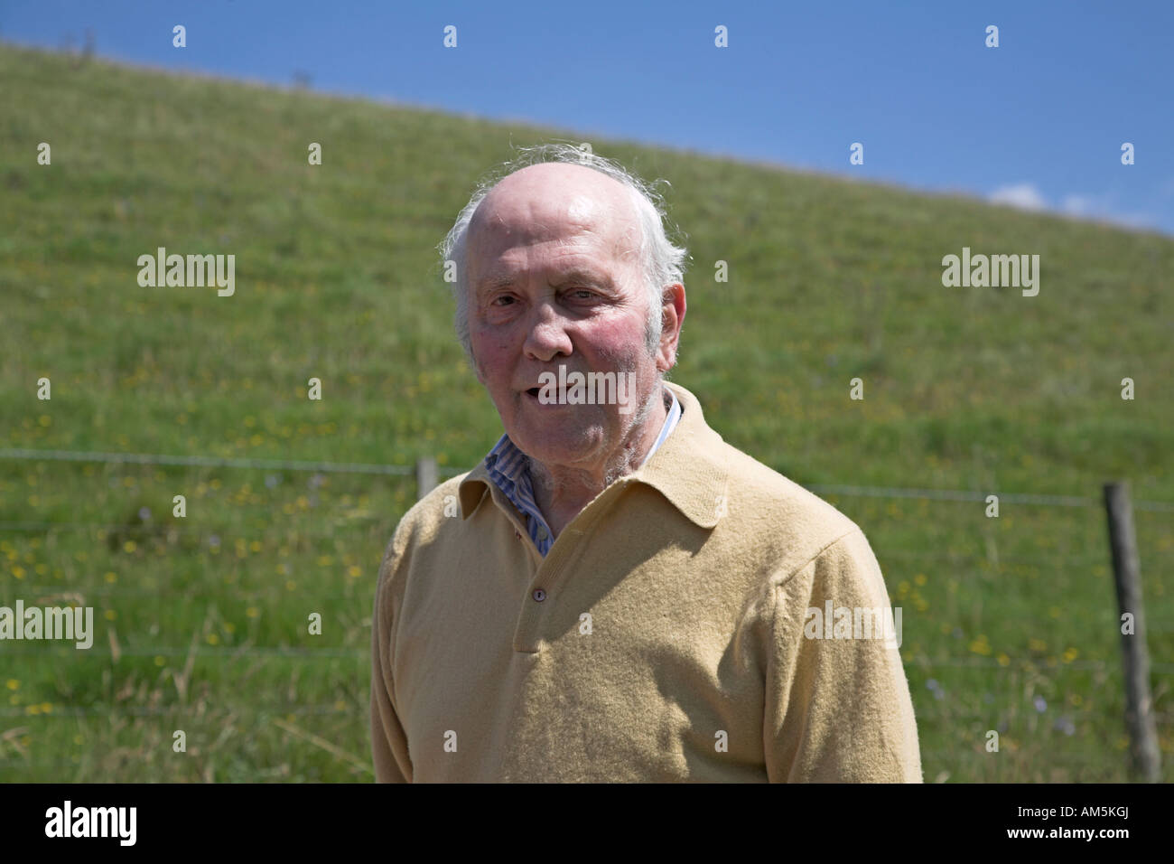 Portrait of elderly man in the countryside in front of green grassy ...