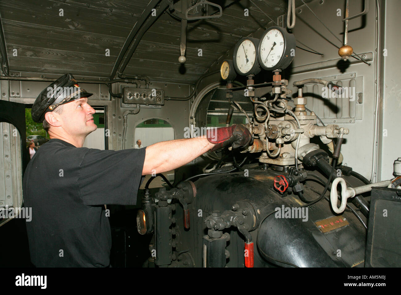 Engine driver adjusting the steam pressure in an historical steam train ...