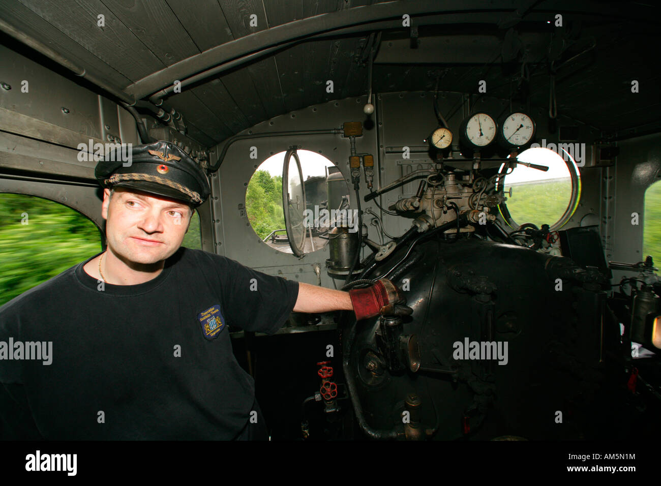 Engine driver adjusting the steam pressure in an historical steam train ...