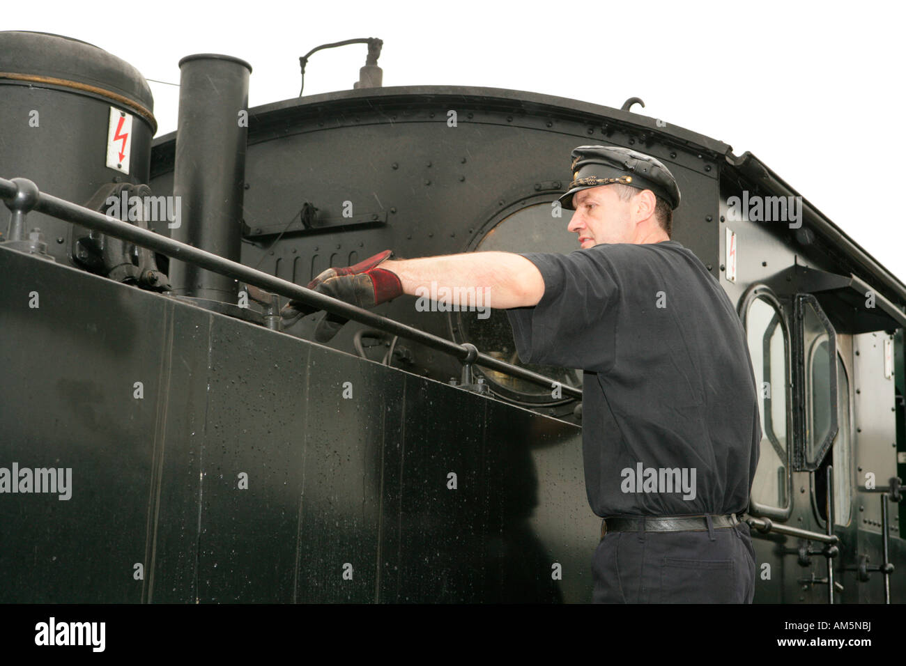Engine driver cleaning historical steam train Stock Photo - Alamy
