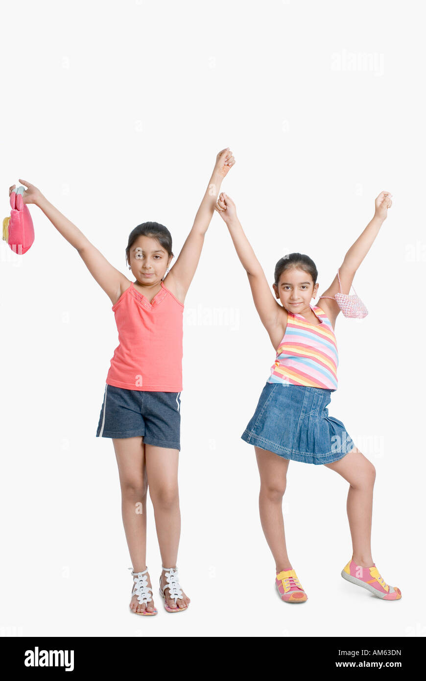 Portrait of two girls posing with arms raised Stock Photo - Alamy
