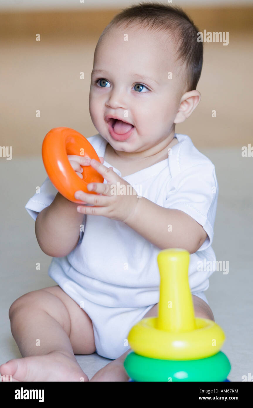 Close-up of a baby boy playing with stacking rings and smiling Stock ...