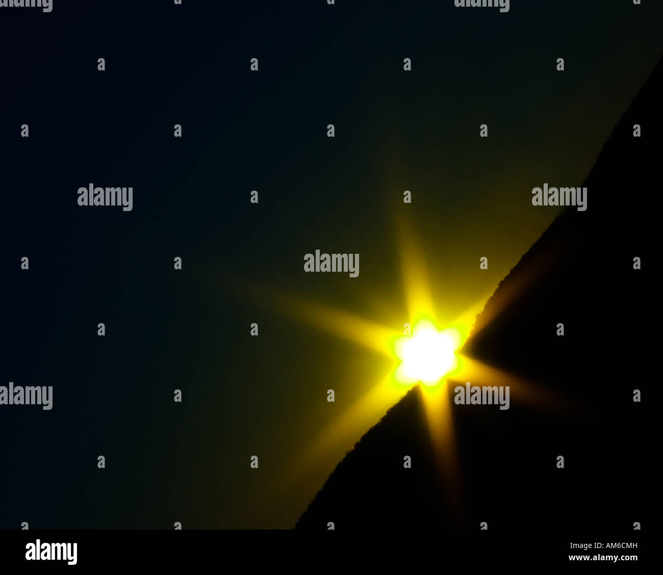Sun disappearing behind the far off mountains Stock Photo - Alamy