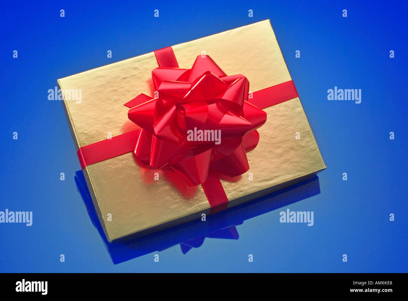 Shiny gold gift box with bright red ribbon Stock Photo - Alamy