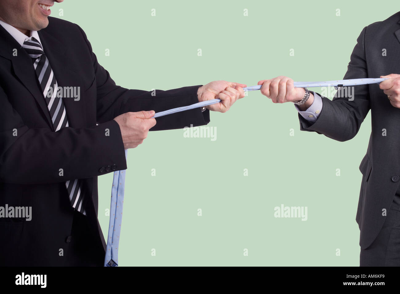 Two businessmen fighting a tug of war with a necktie Stock Photo - Alamy