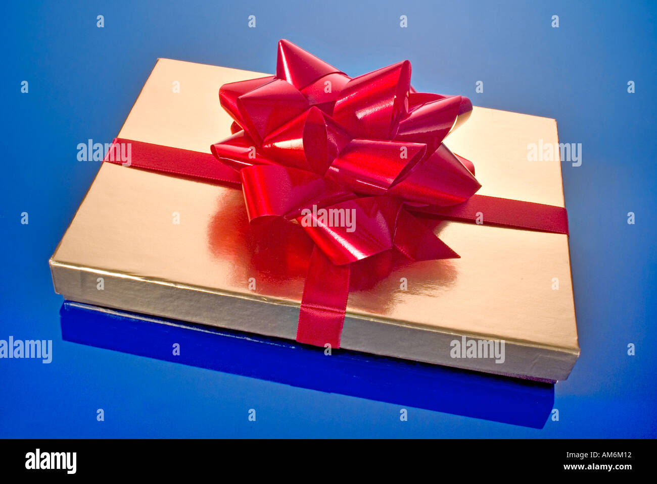 Gold gift box with big shiny red bow Stock Photo - Alamy
