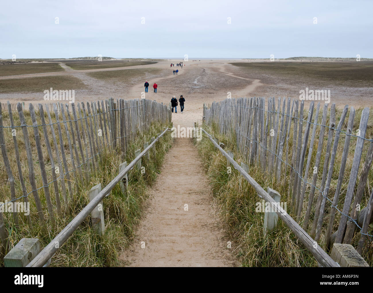 Boardwalk pathway down to beach with picket fence and people walking ...