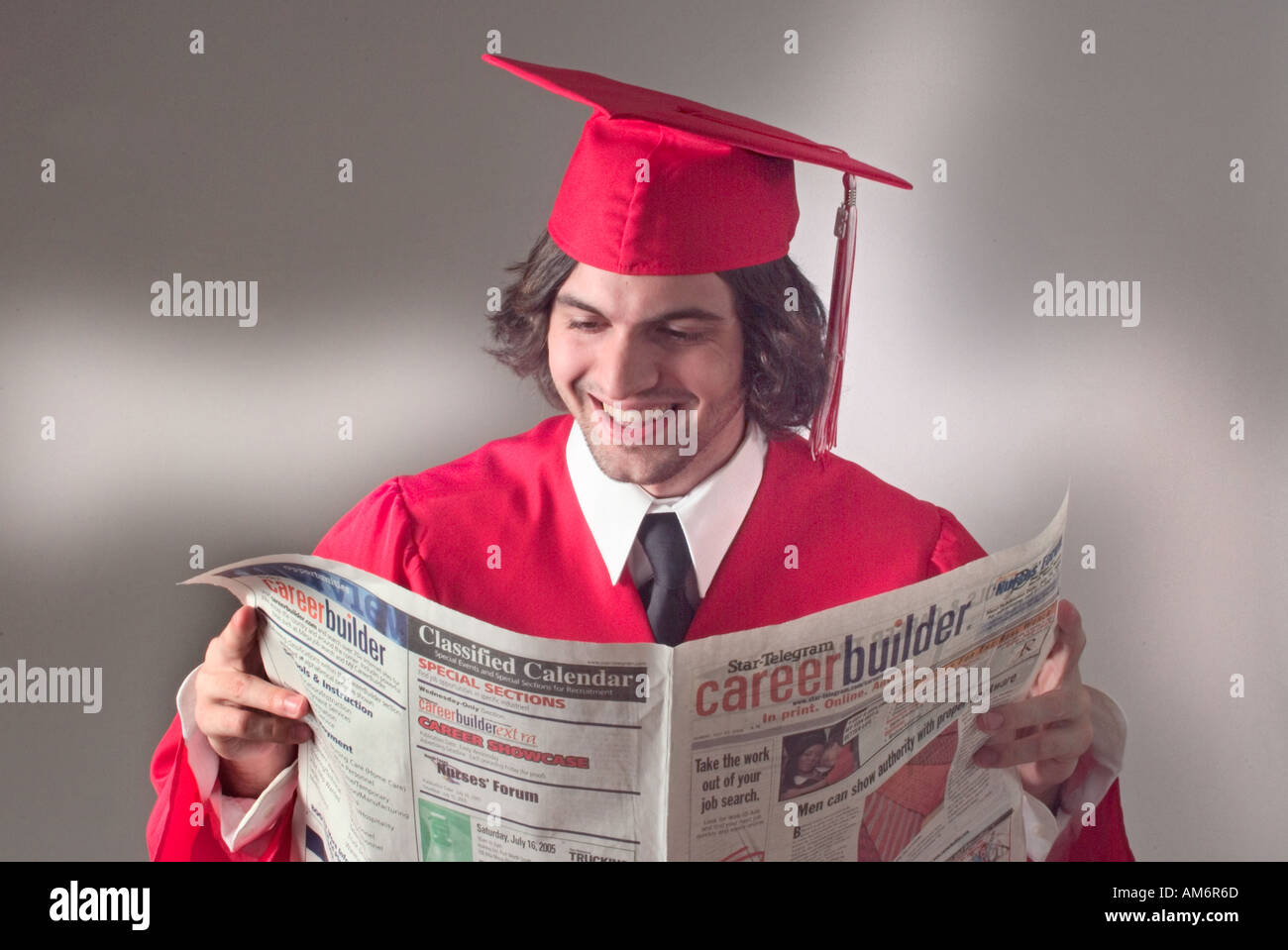 Happy Graduate in Cap and Gown Reading Want Ads Stock Photo - Alamy