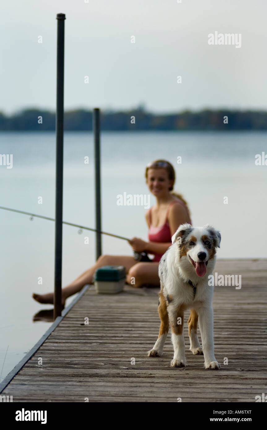A girl with her dog fishing on a dock Stock Photo - Alamy