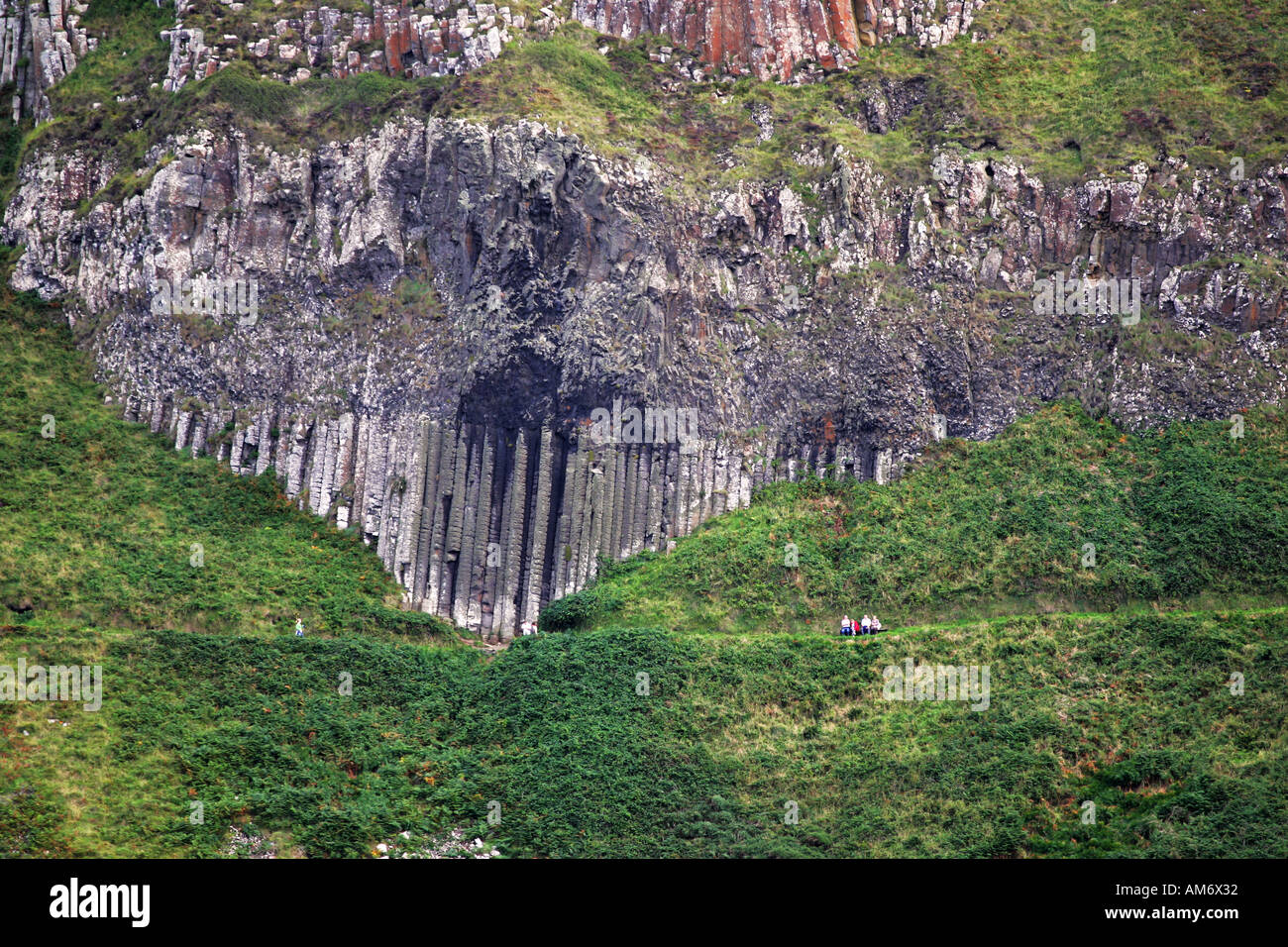 Tourists hike on the coastal path beneath the Giants Organ, Giants ...