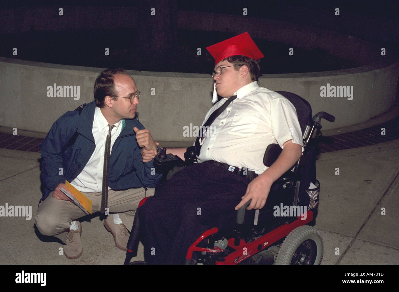 Handicapped graduate in wheelchair and teacher talking ages 45 and 18 ...