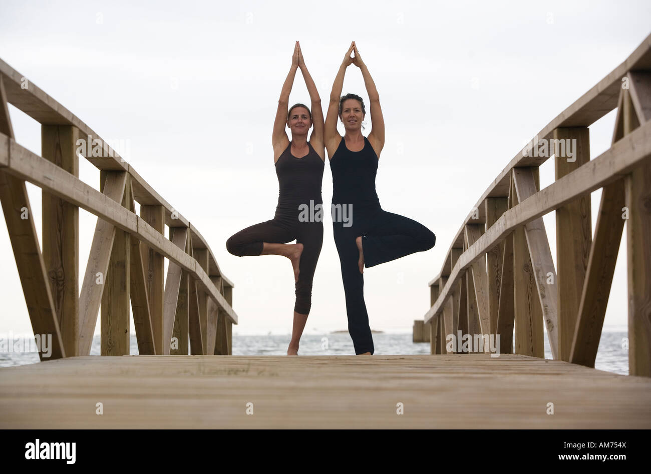 two women to a balance yoga pose Stock Photo - Alamy