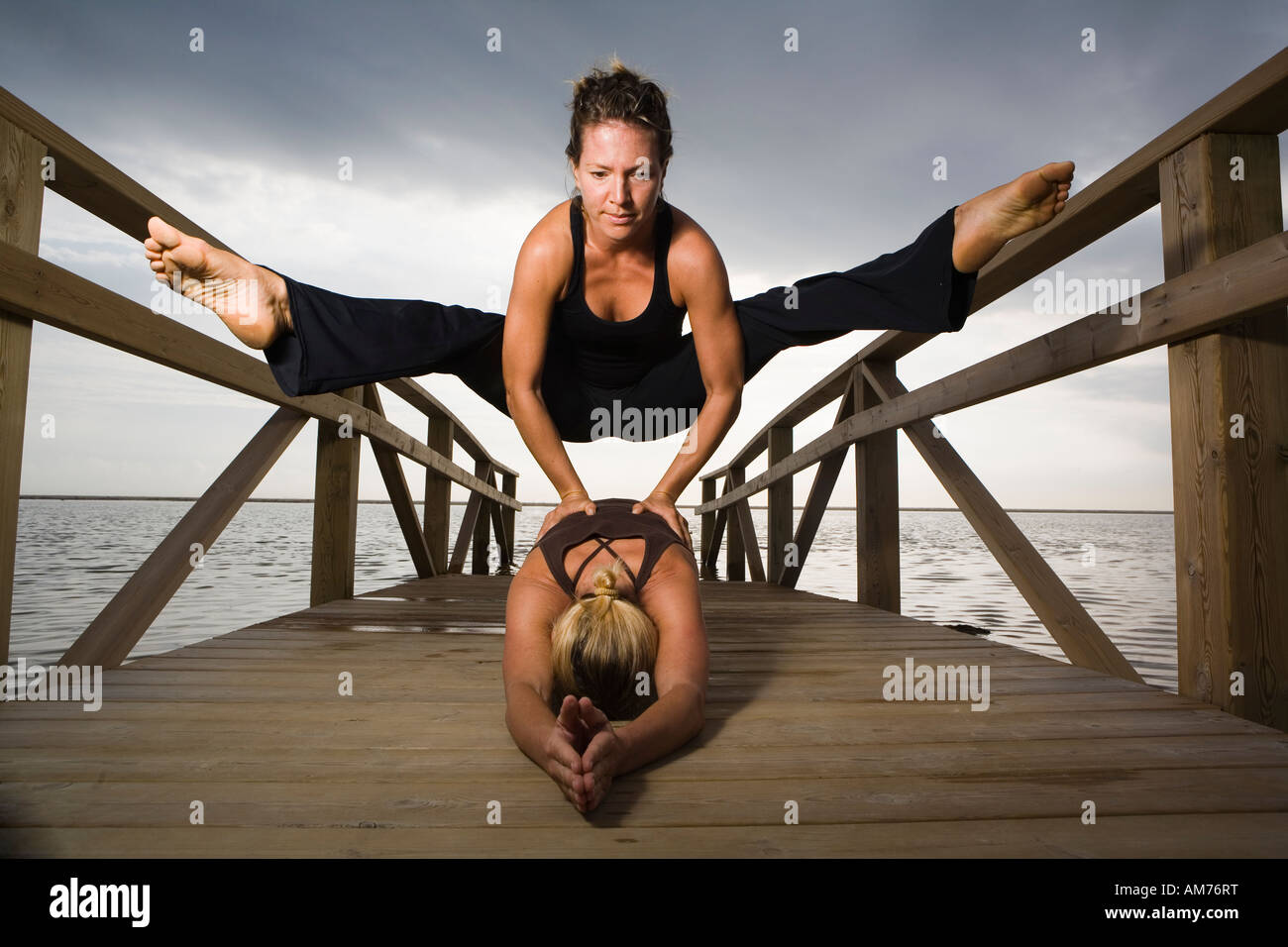 two woman practice couple yoga in balance and strength pose Stock Photo ...