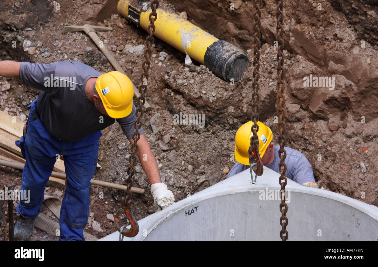Construction workers at roadworks helping each other with building a ...
