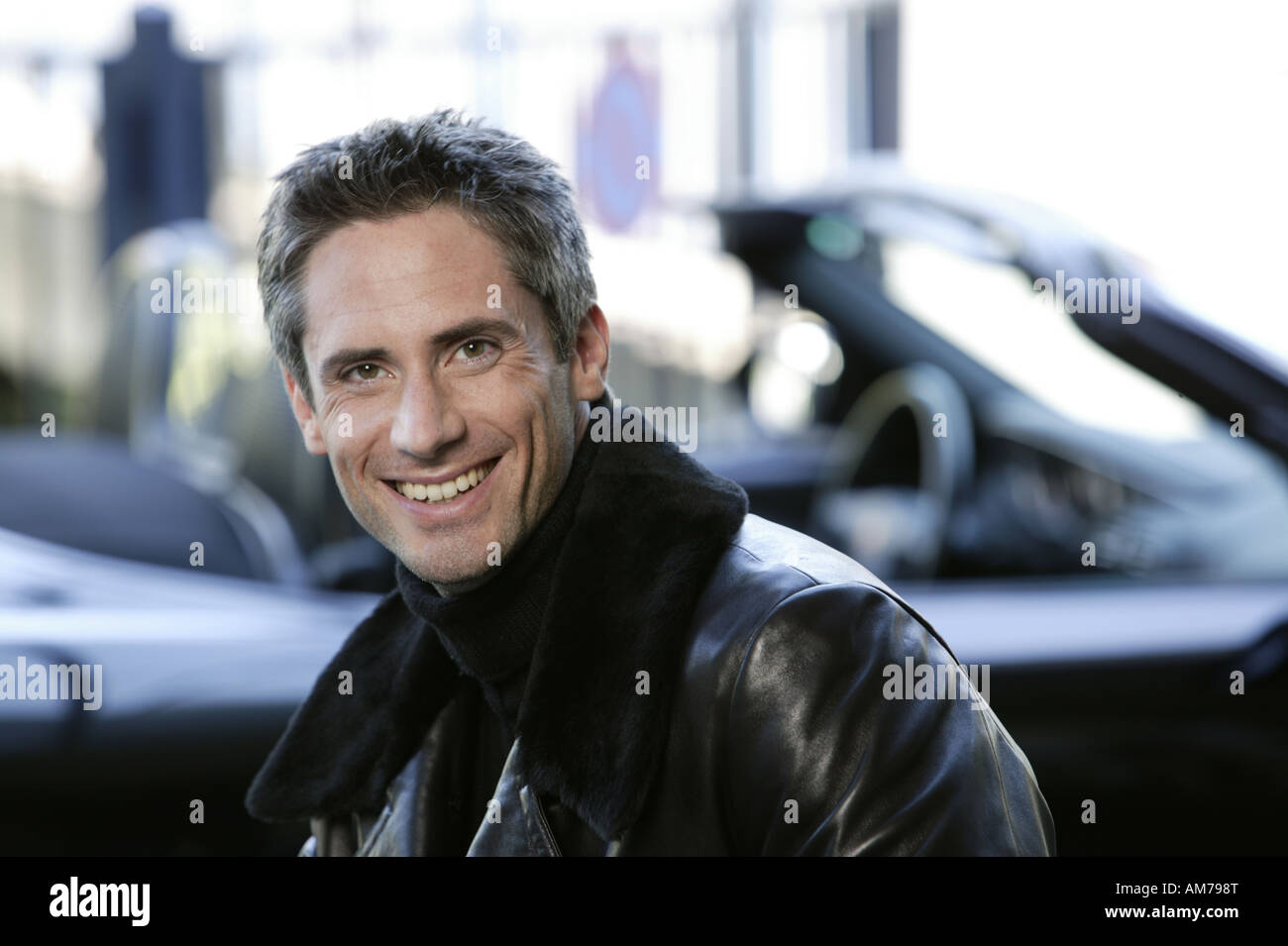 Man in leather jacket in front of his sports car Stock Photo - Alamy