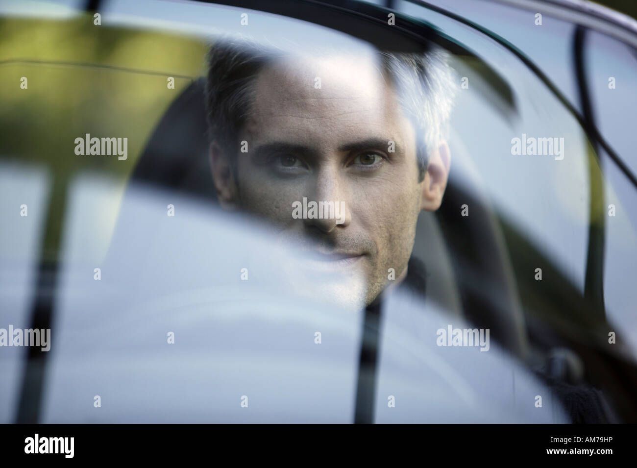 Portrait of a man in a black convertible, seen through the windscreen ...