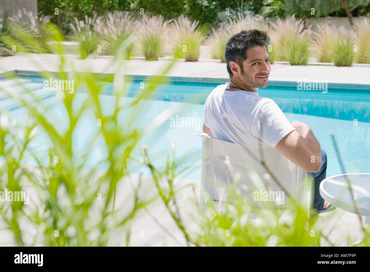 Man relaxing by swimming pool Stock Photo - Alamy
