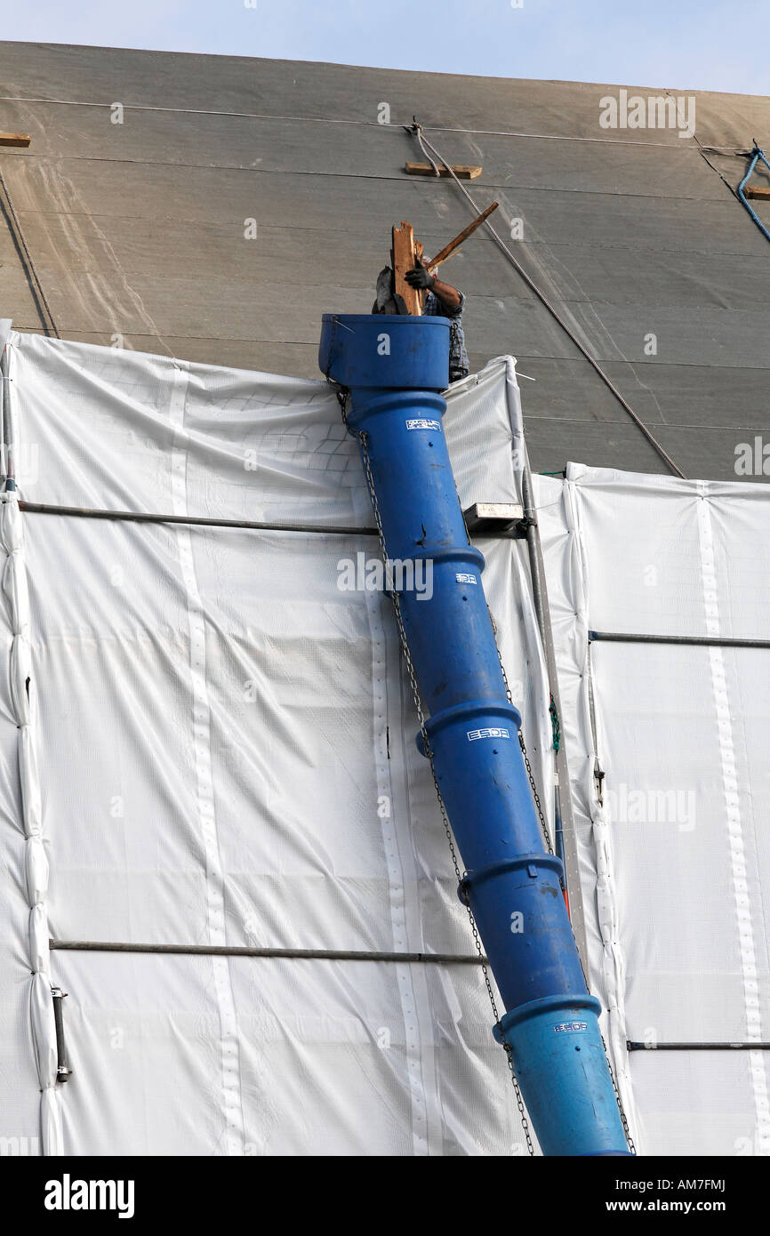 Construction worker at the top of a building, throwing wooden trash ...