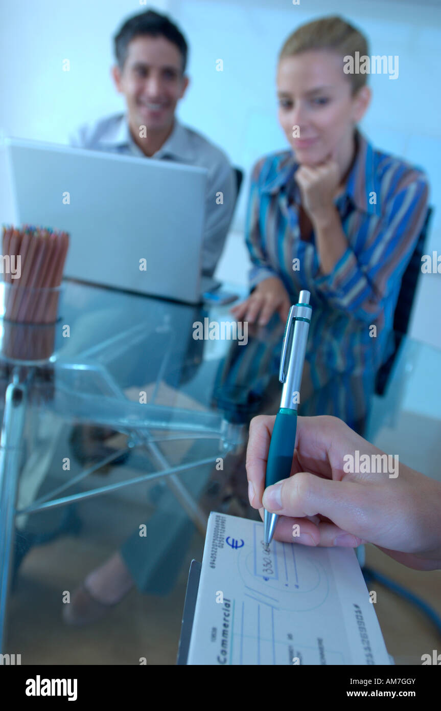 Person making out check with business people smiling in background ...