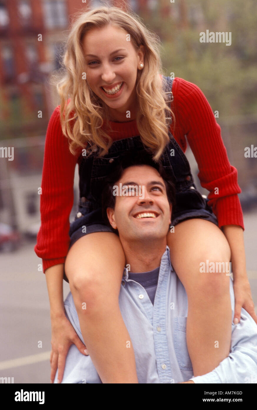 Young woman sitting on man's shoulders, smiling Stock Photo - Alamy