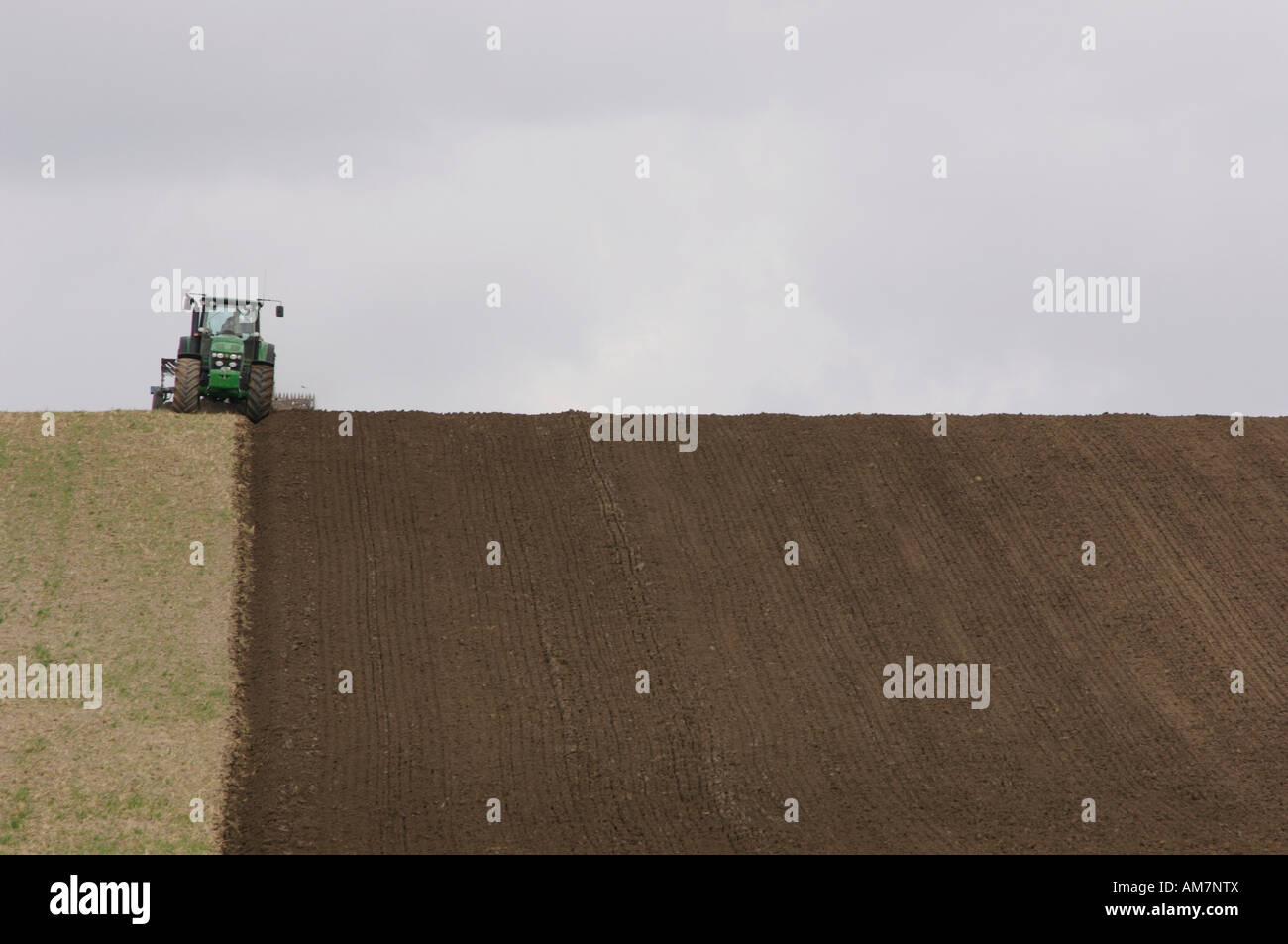 Agricultural landscape with a tractor ploughing Stock Photo - Alamy