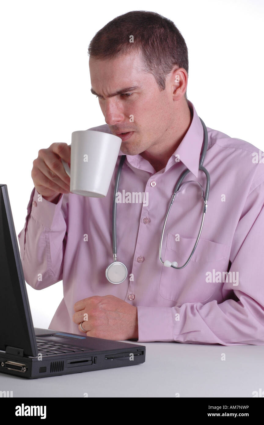 A young male doctor grabs a coffee at his desk during a long shift ...