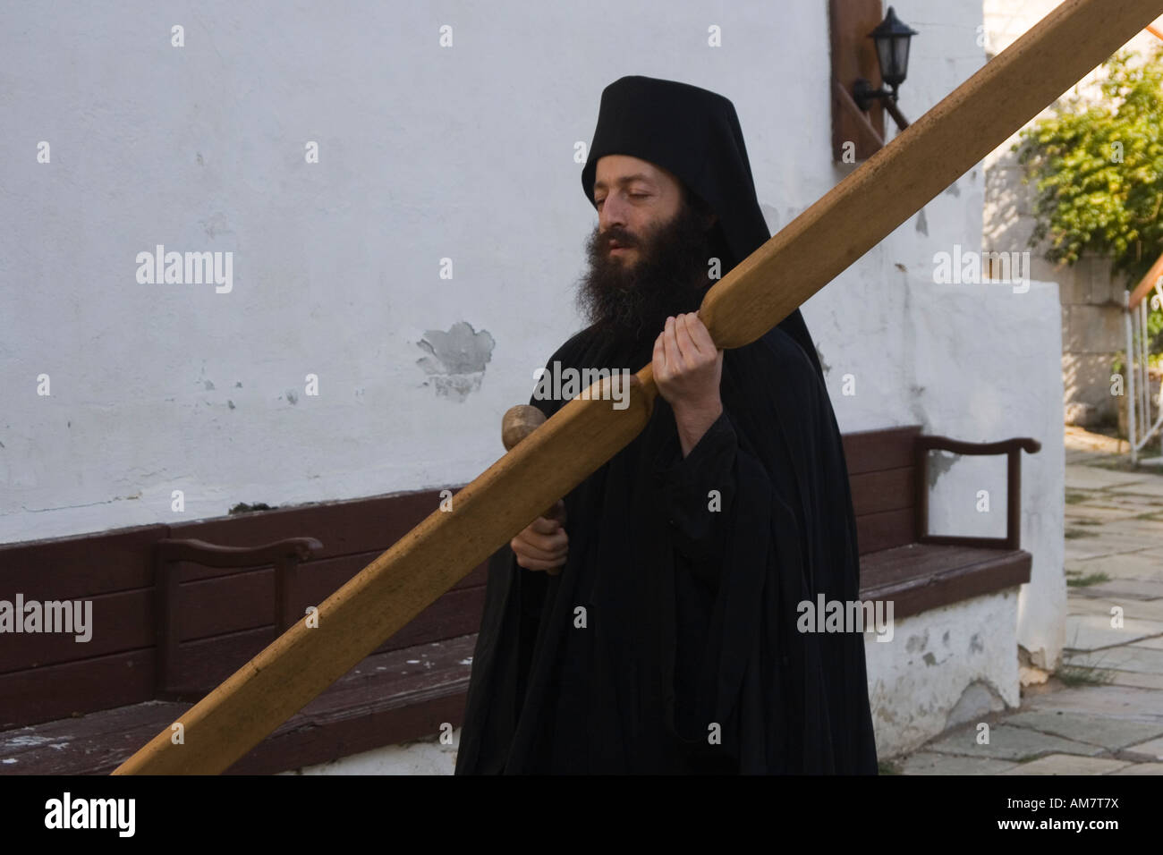 Orthodox monk calls to evening prayer by striking a wooden semantron ...
