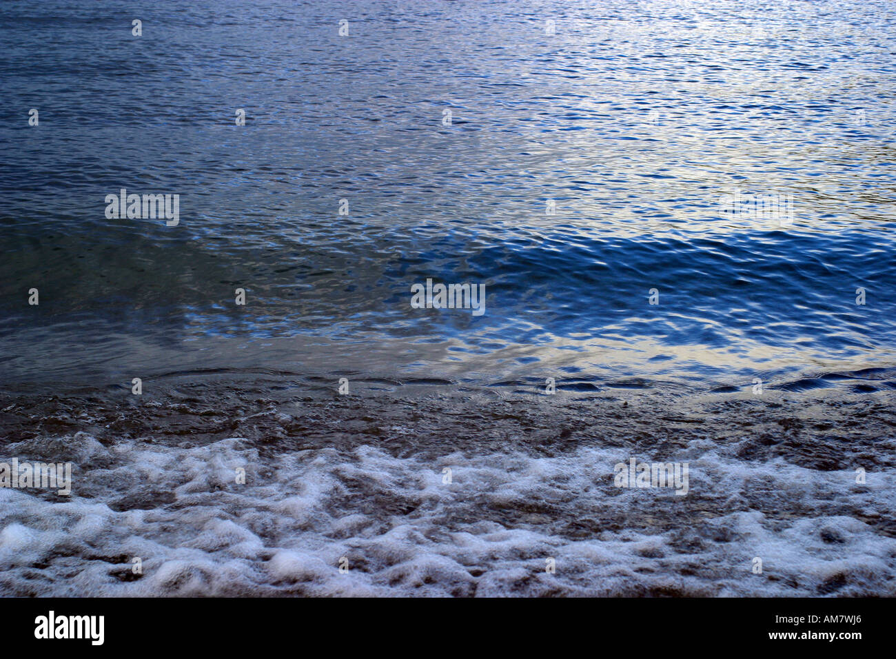 Sun reflecting off the ocean water surface with a wave approaching ...