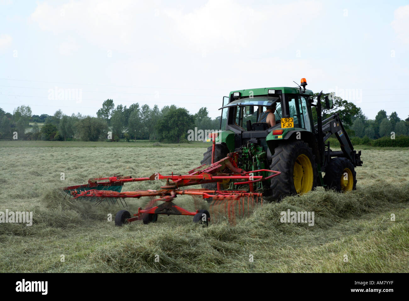 Farmer turning hay with tractor and tedder 1 Stock Photo - Alamy
