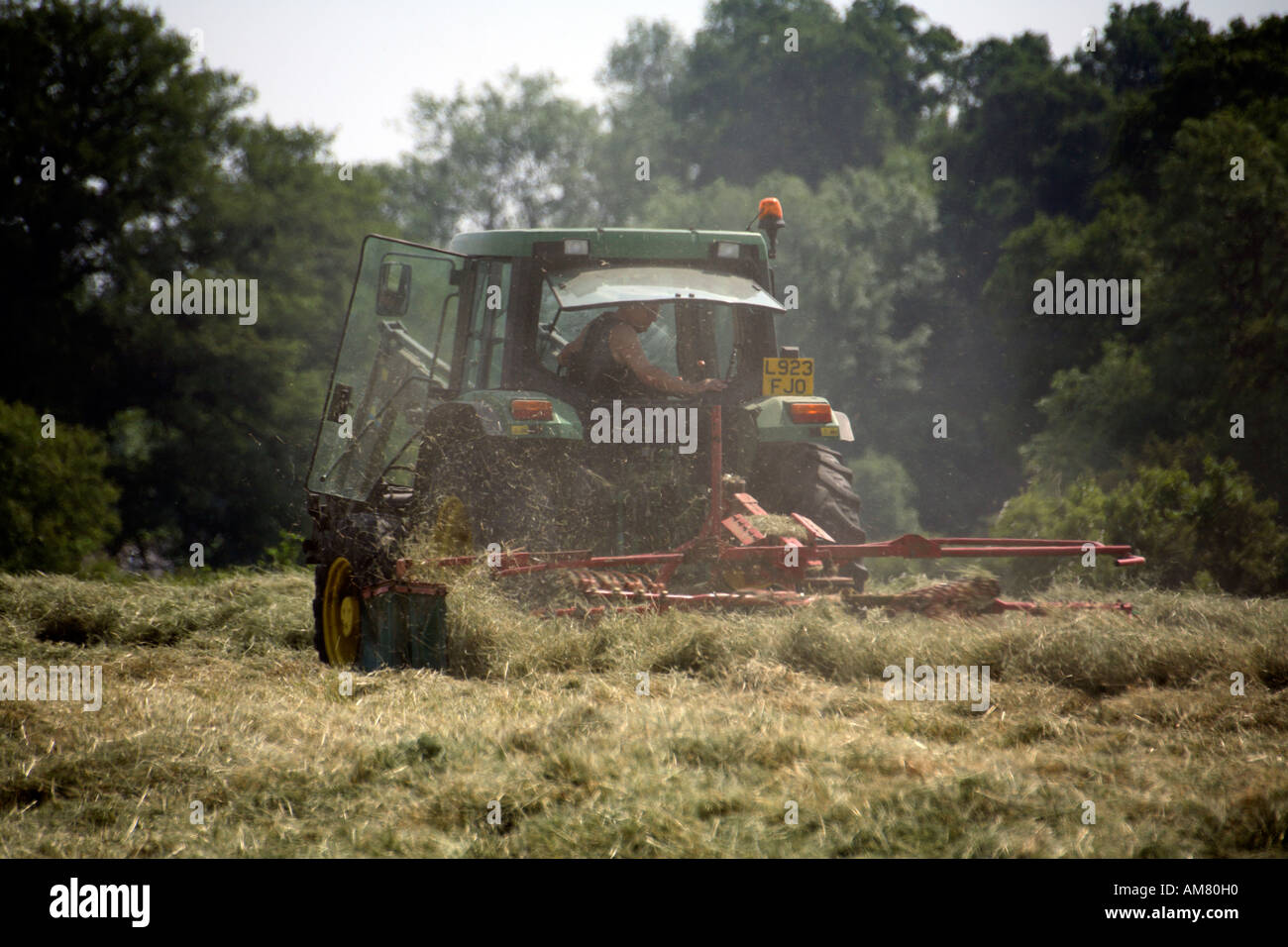 Farmer with tractor and rake rowing hay in summer meadow 4 Stock Photo ...