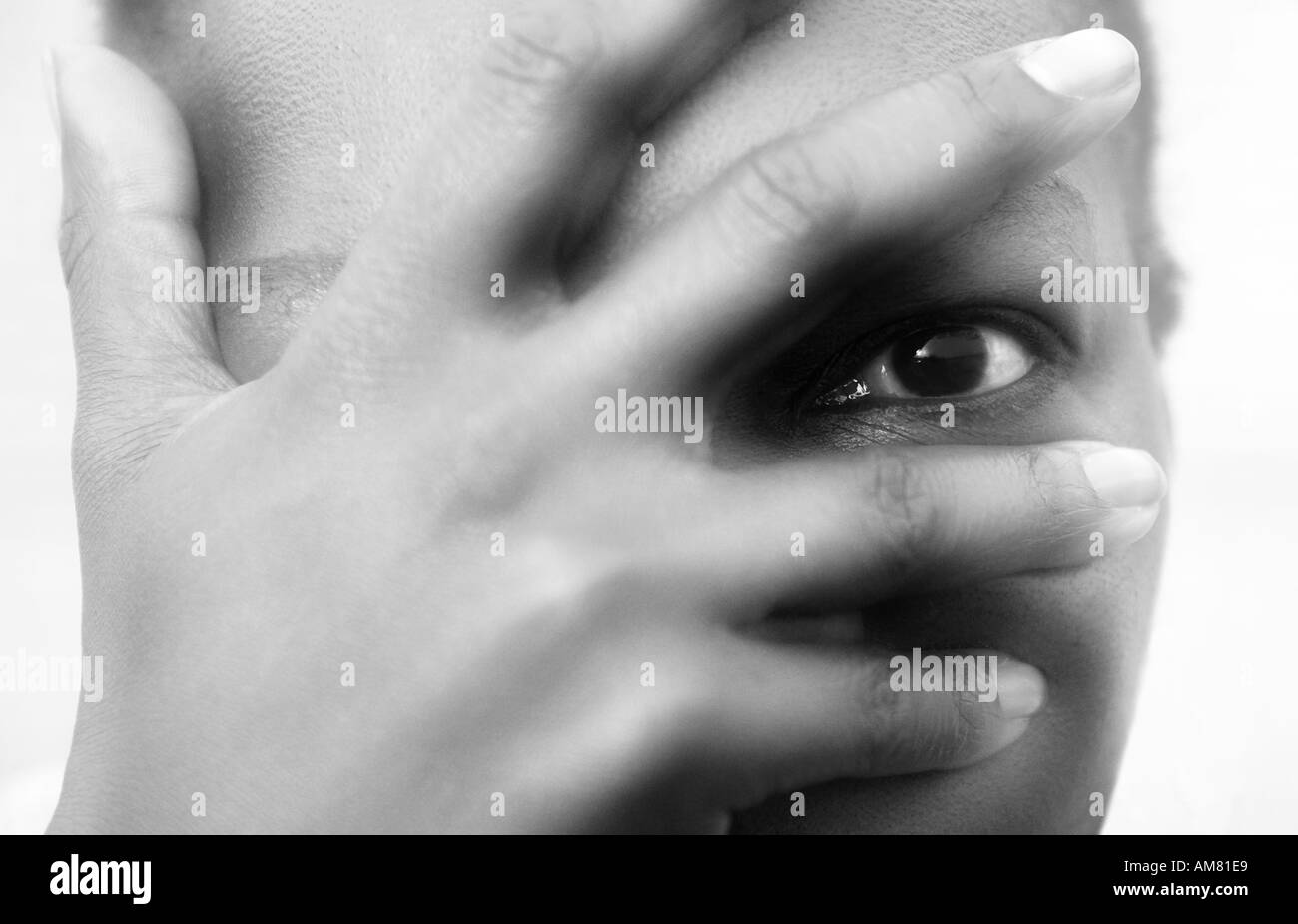 Girl peeping through the fingers of one hand Stock Photo - Alamy