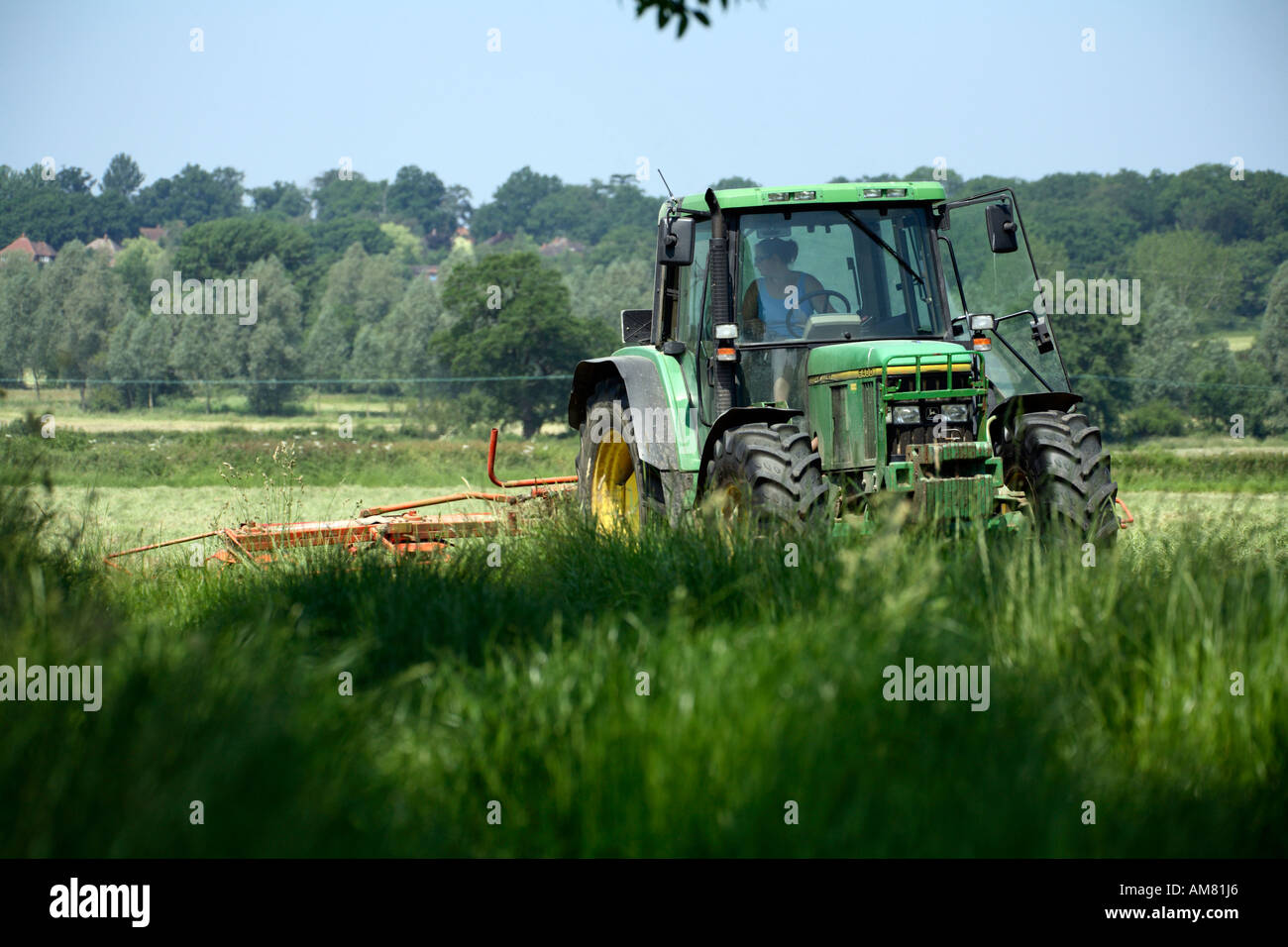 Female farm worker in tractor turning hay in summer 2 Stock Photo - Alamy