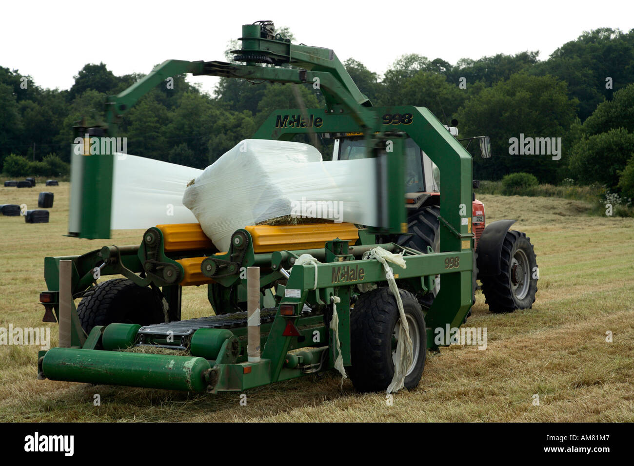 Wrapping big hay bales with tractor and trailer in summer meadow 5 ...