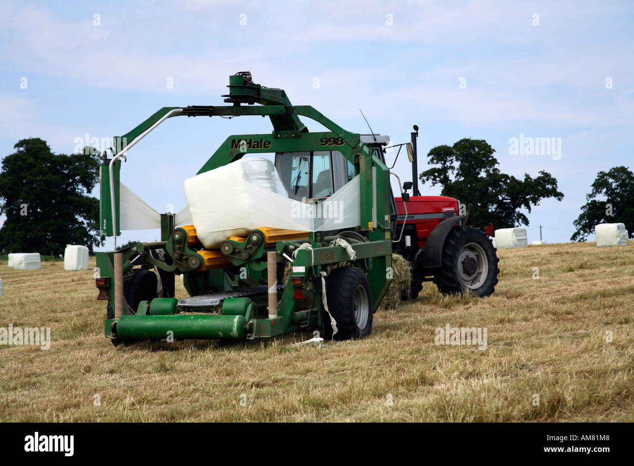 Wrapping big hay bales with tractor and trailer in summer meadow 6 ...