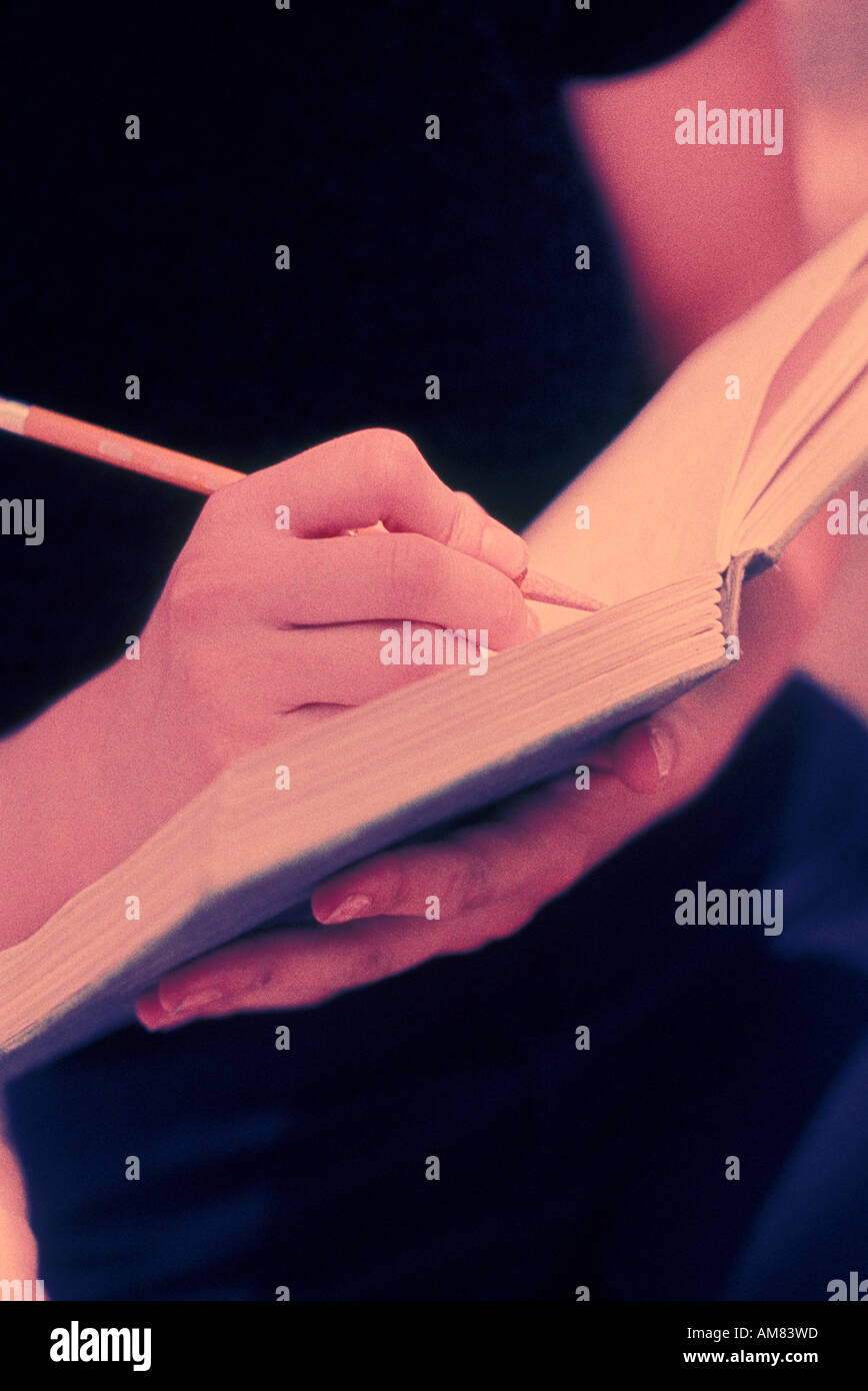 Young woman writing on book Stock Photo - Alamy