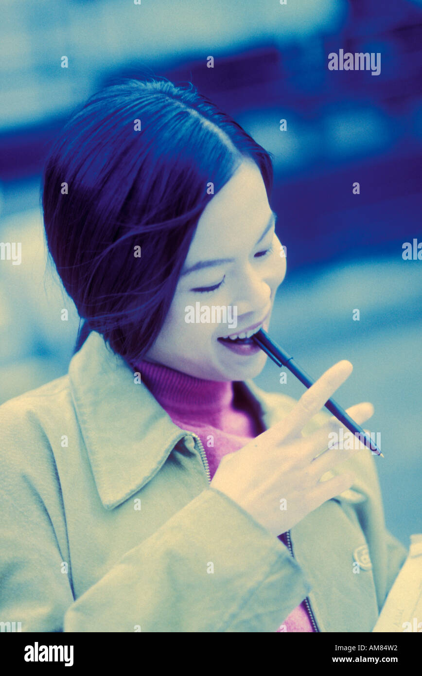 Young woman biting pen hi-res stock photography and images - Alamy