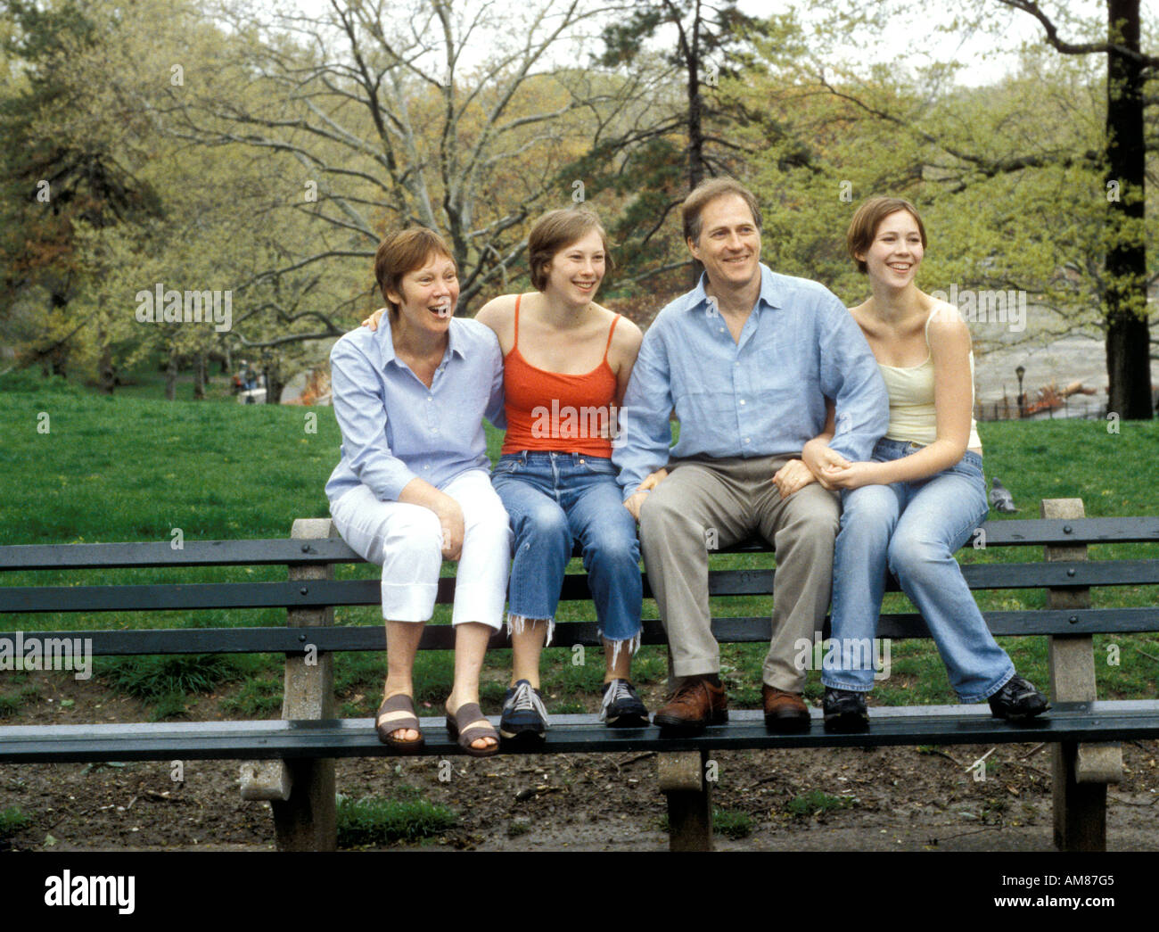Family sitting on bench, smiling Stock Photo - Alamy