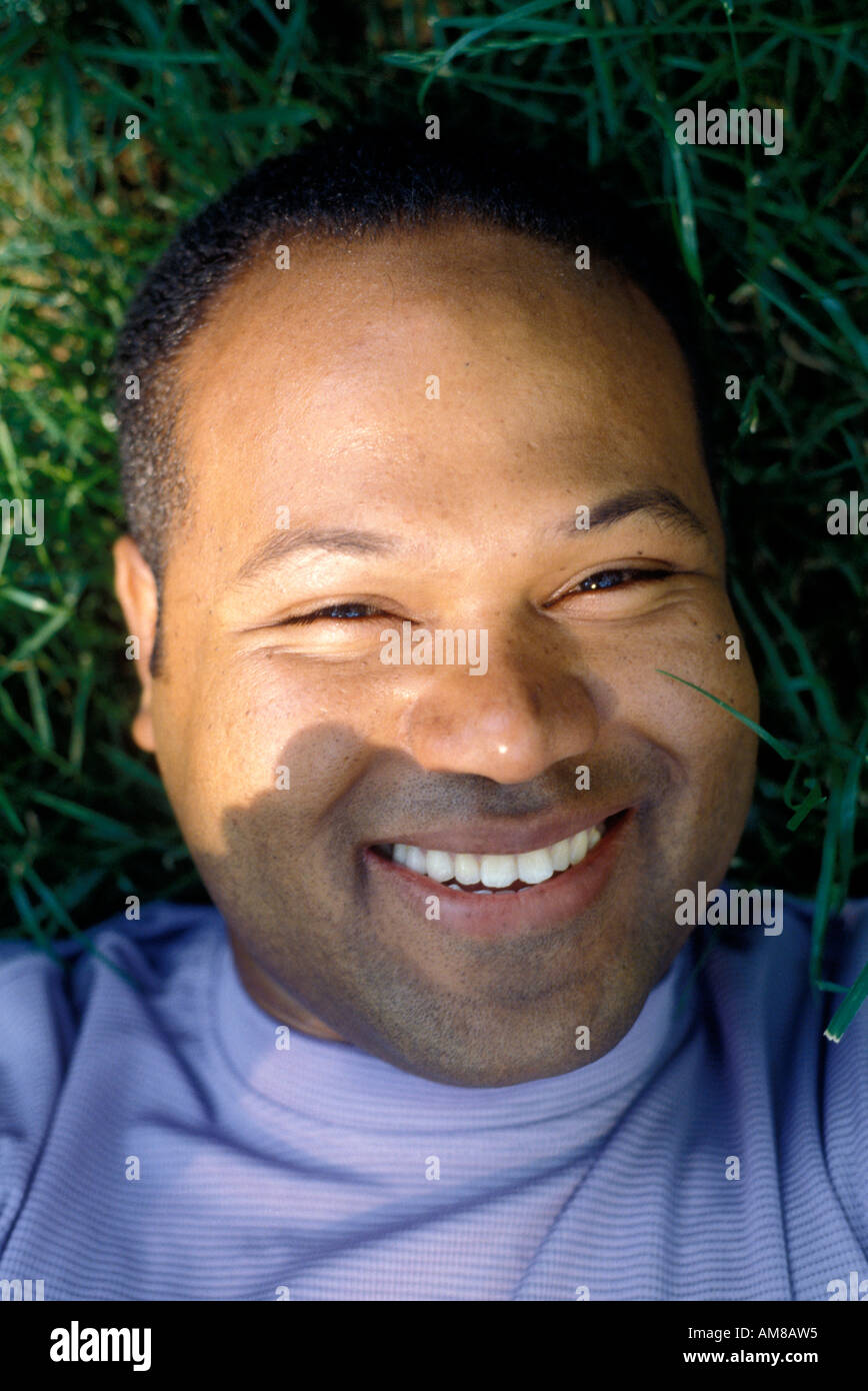Mid adult man lying on grass, smiling, portrait Stock Photo - Alamy