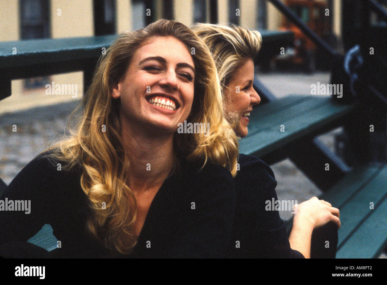Young women sitting on bench, smiling Stock Photo - Alamy