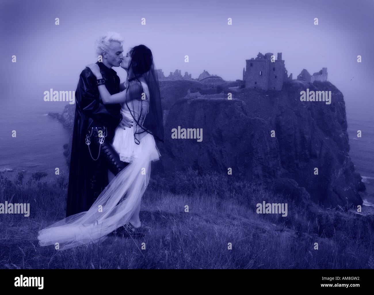 A blue tone romantic image of a gothic couple standing atop a coastal ...