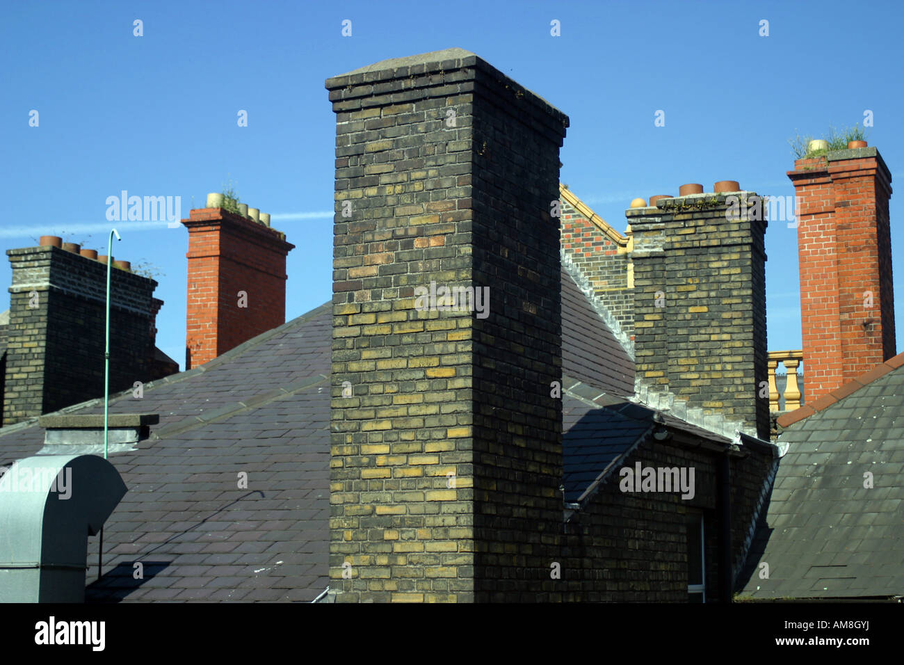 Five chimneys on top of roofs in the blue summer sky Stock Photo - Alamy