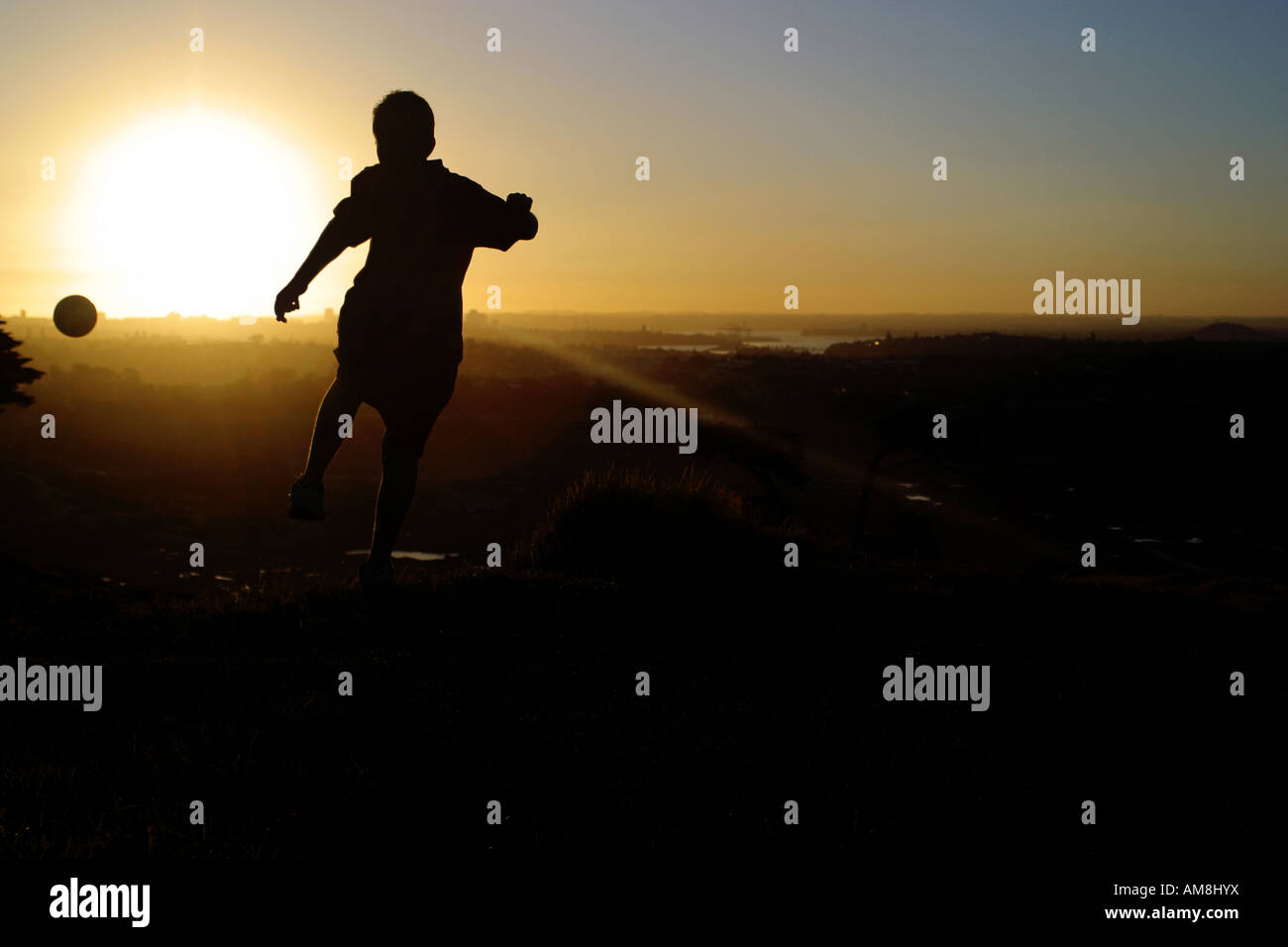 young man kicking a football into the sunset Stock Photo - Alamy